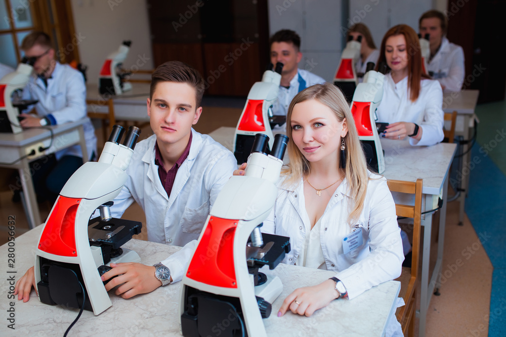 forensic examination. Young scientist looking through a microscope in a ...