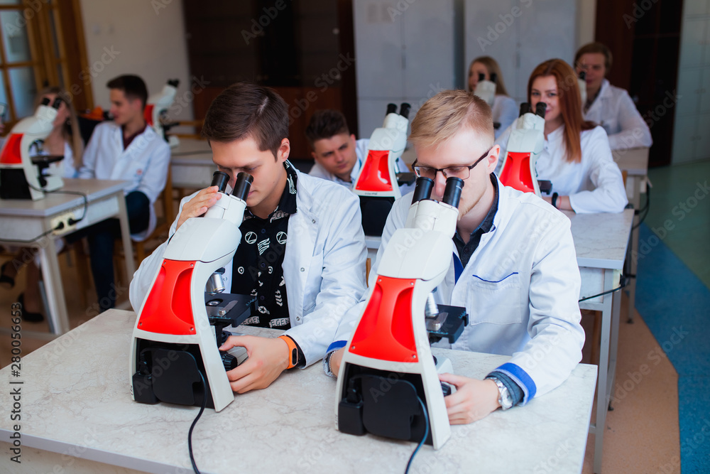 forensic examination. Young scientist looking through a microscope in a ...