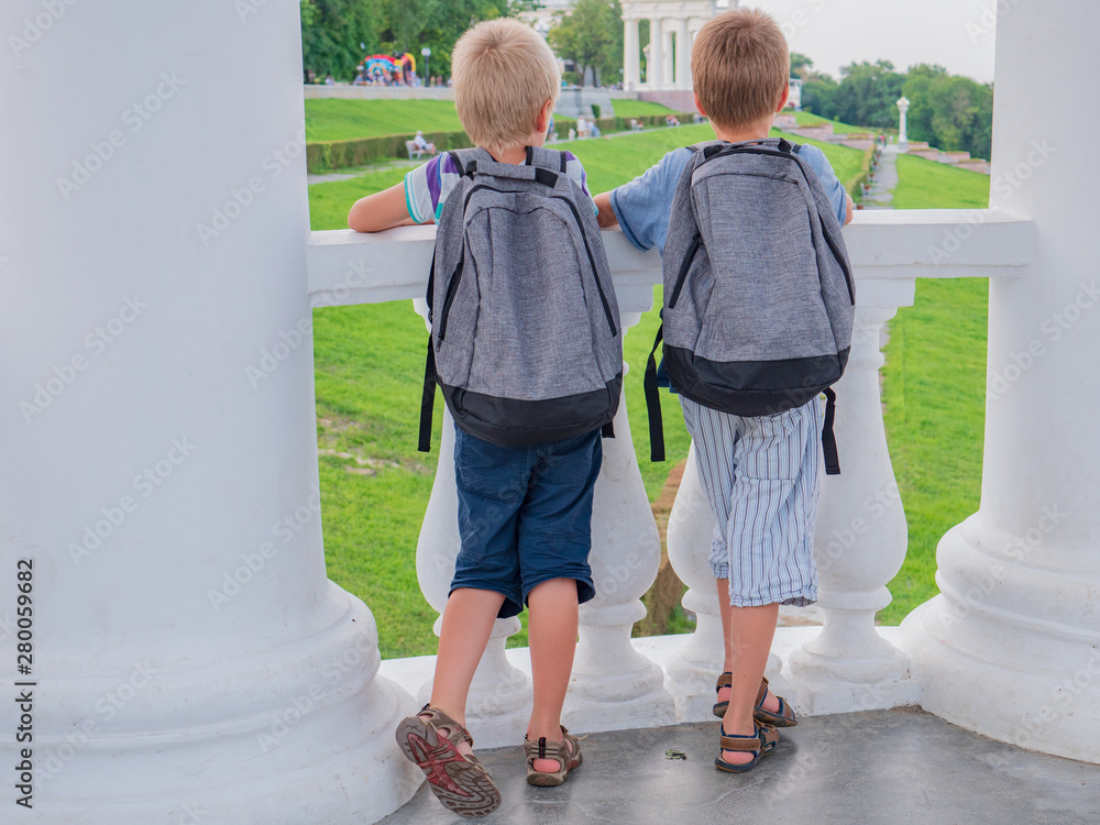 Children with school bags walk along the promenade. Happy pupil go back ...