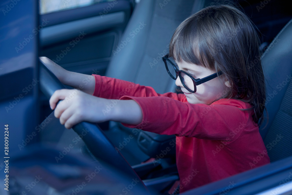 Dangers and risks of underage driving. A little child girl driving a ...