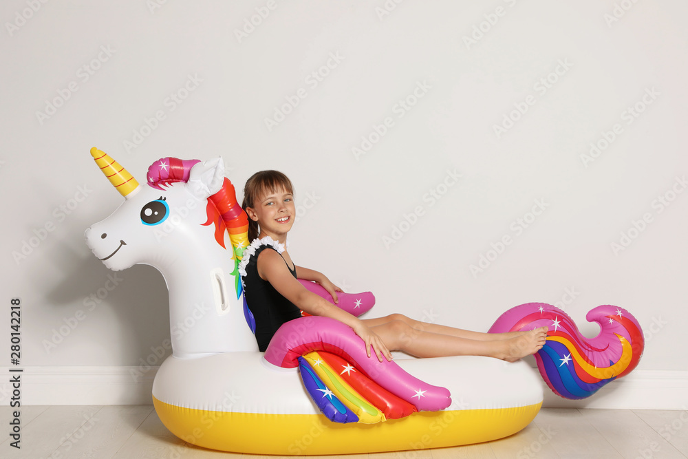Cute little girl on bright inflatable ring near light wall Stock Photo ...