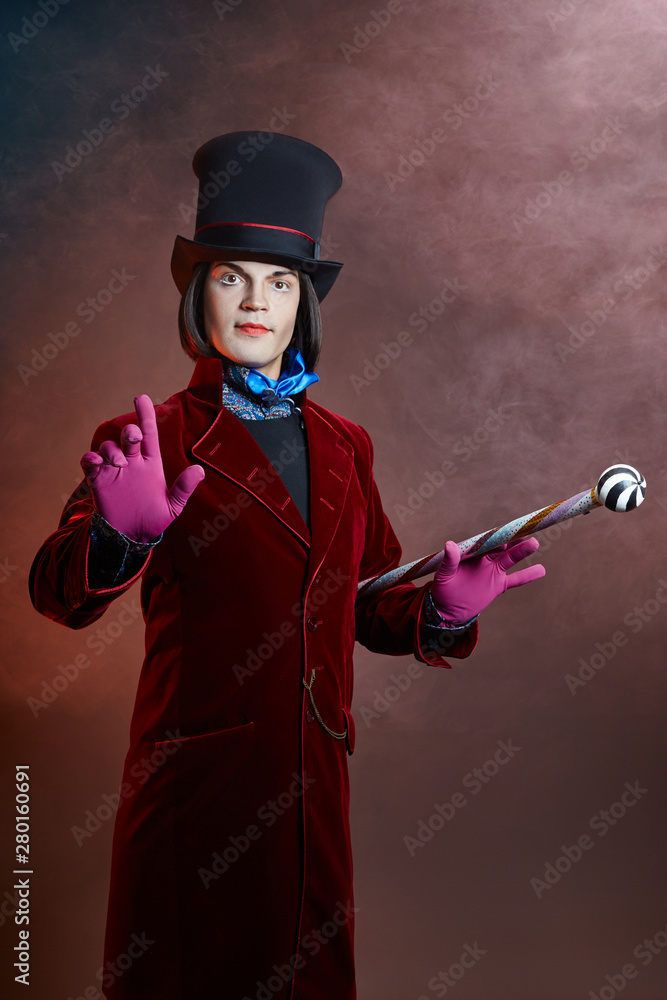 Fabulous circus man in a hat and a red suit posing in the smoke on a ...