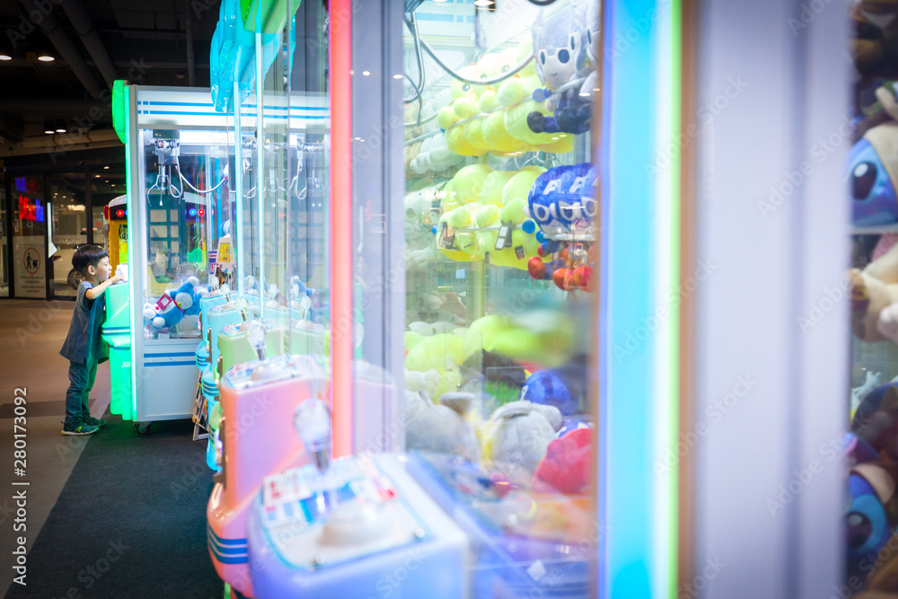 An adorable little asian boy playing an arcade claw machine in kids ...