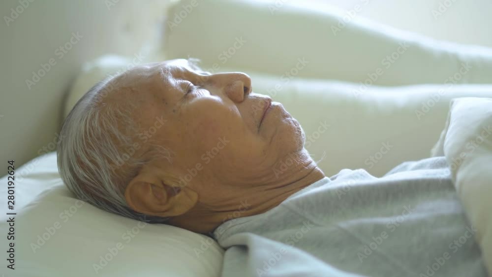 Senior man with grey hair and wrinkled face sleeping on the bed at home ...