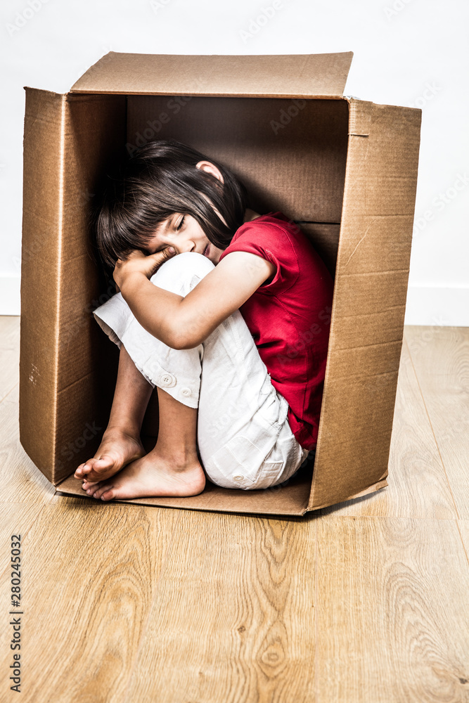 sad crying, tired child hunched in small box for refuge Stock Photo ...