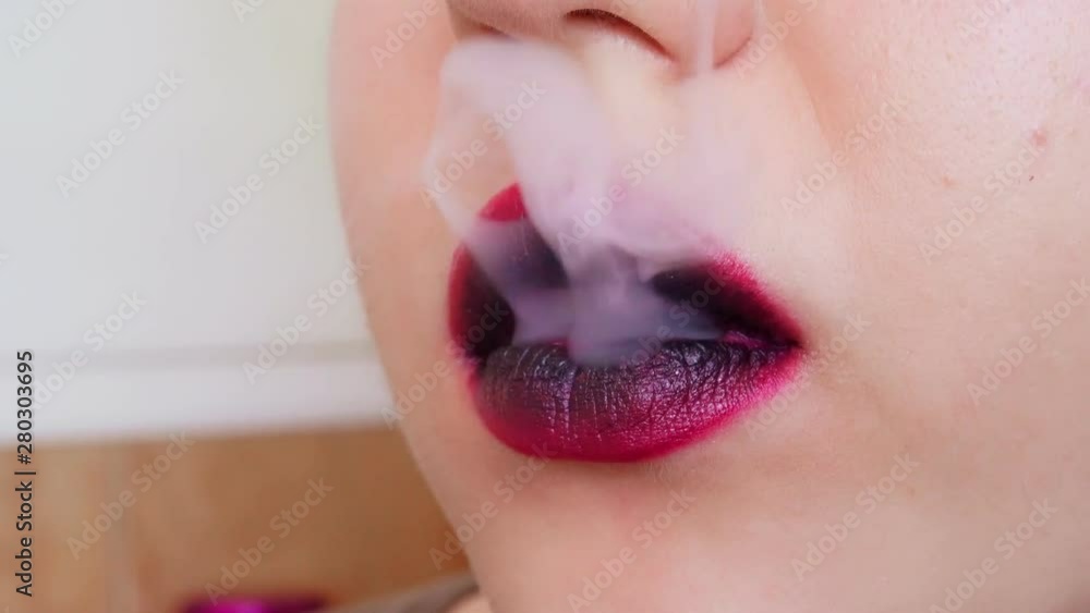 Stockvideo Extreme close-up of lips of a young woman. A woman smokes a ...