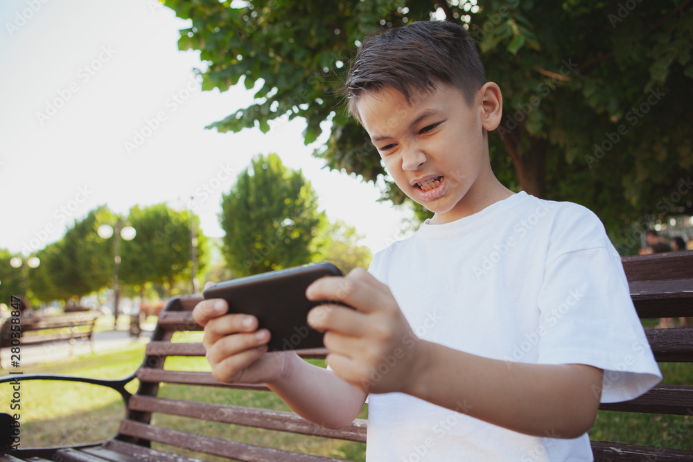 Low angle shot of a young Asian boy looking angry, playing online games ...