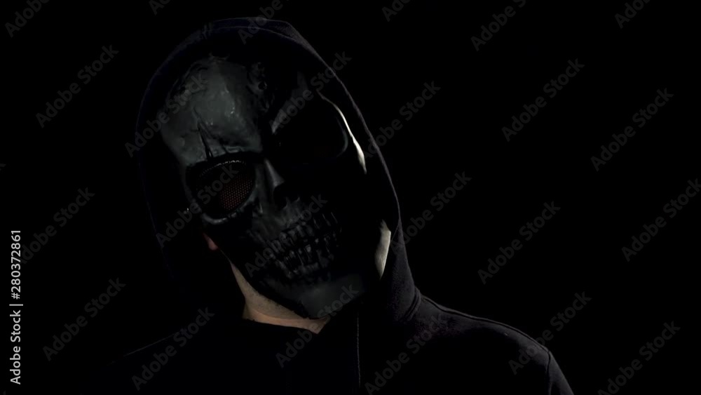 Portrait of spooky man in black skull mask looking in camera and scary ...