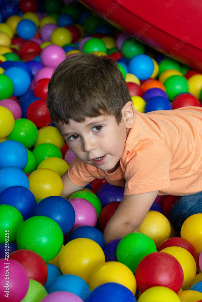 Child playing in ball pit. Kindergarten or preschool play room. Cute ...