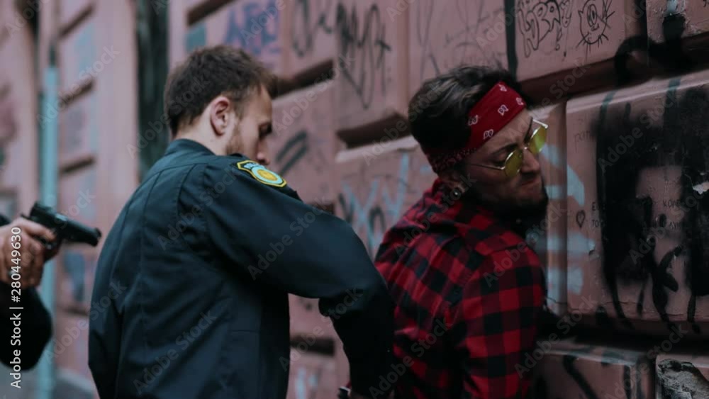 Slow motion policeman with pistol arrest robber in handcuffs standing ...