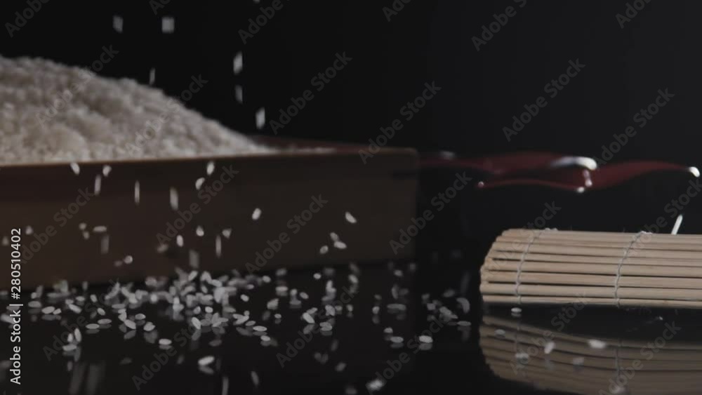 White rice is falling down on the black table. The rice is falling down ...