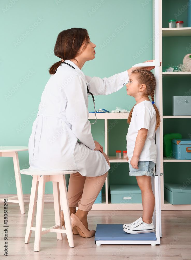 Female doctor measuring height of little girl in hospital Stock Photo ...