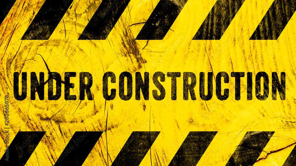 Under construction warning sign text with yellow black stripes painted ...
