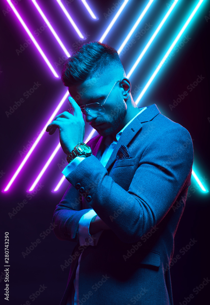 Young handsome model posing in a studio in a trendy neon light ...