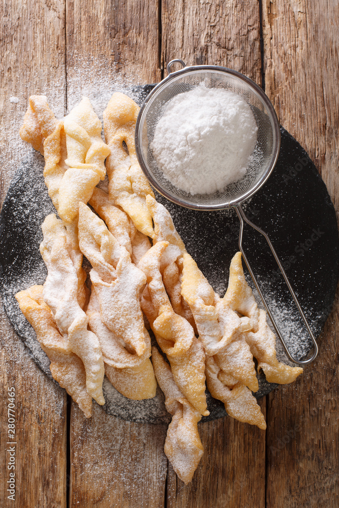 Freshly made Angel Wings Cookies with powdered sugar close-up. Vertical ...