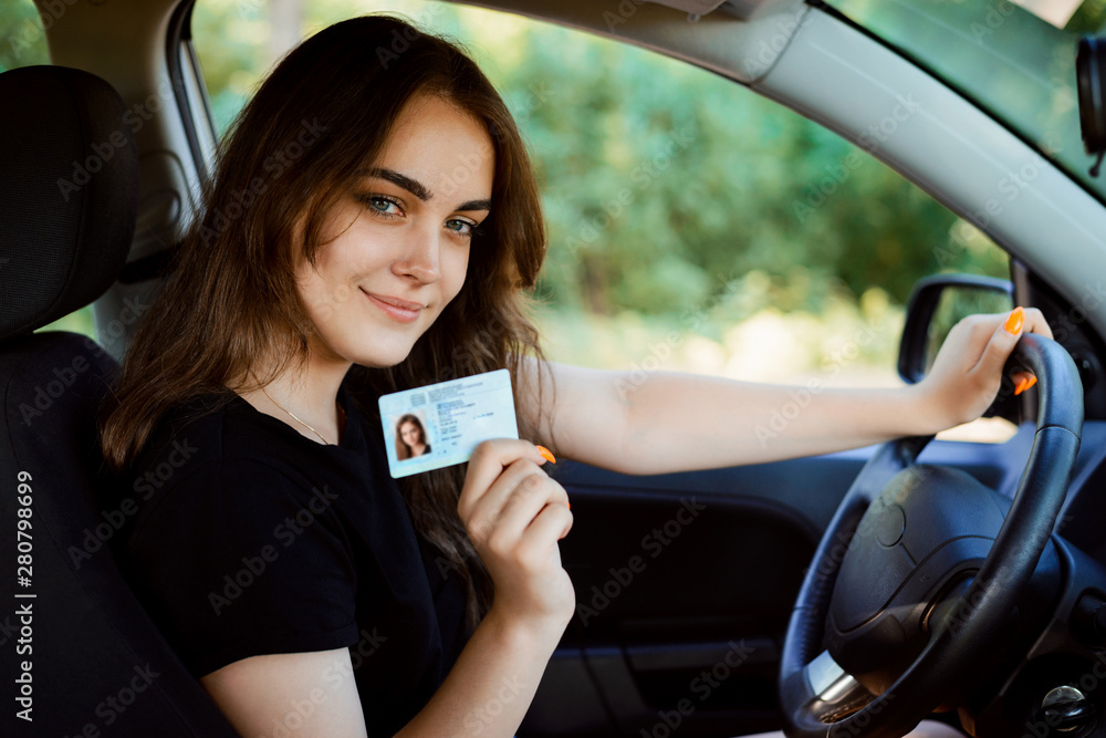 Foto de Young girl with beautiful smile sitting in car showing driving ...
