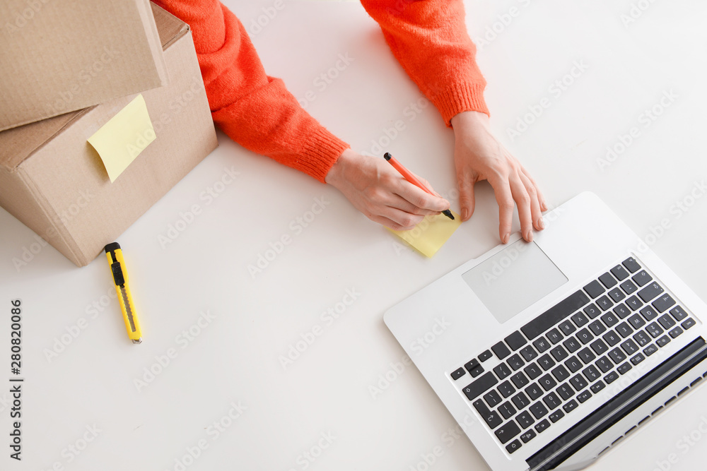 Young woman preparing parcel for client at table Stock Photo | Adobe Stock
