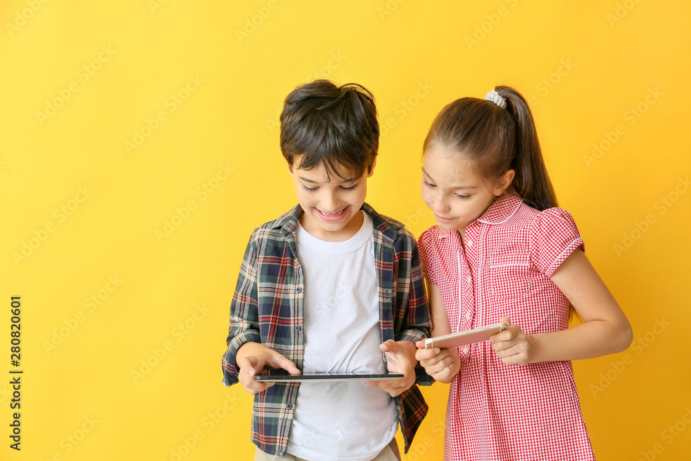 Cute little children with tablet computer and mobile phone on color ...