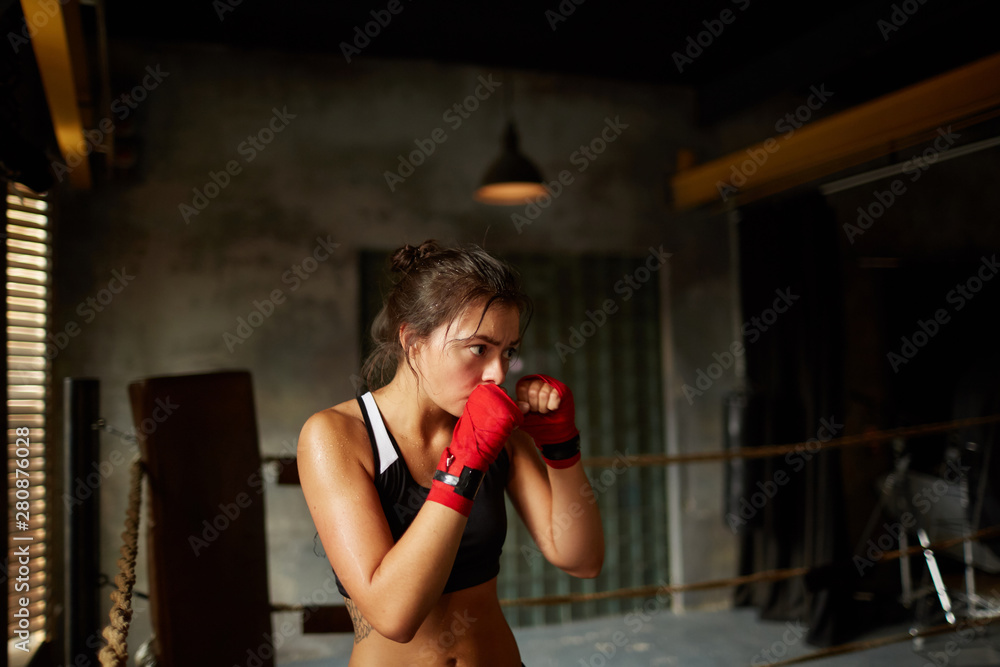Dramatic side view portrait of tough female boxer practicing in boxing ...