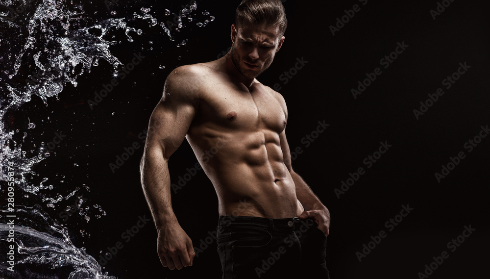 Muscular model sports young man posing on dark background. Fashion ...