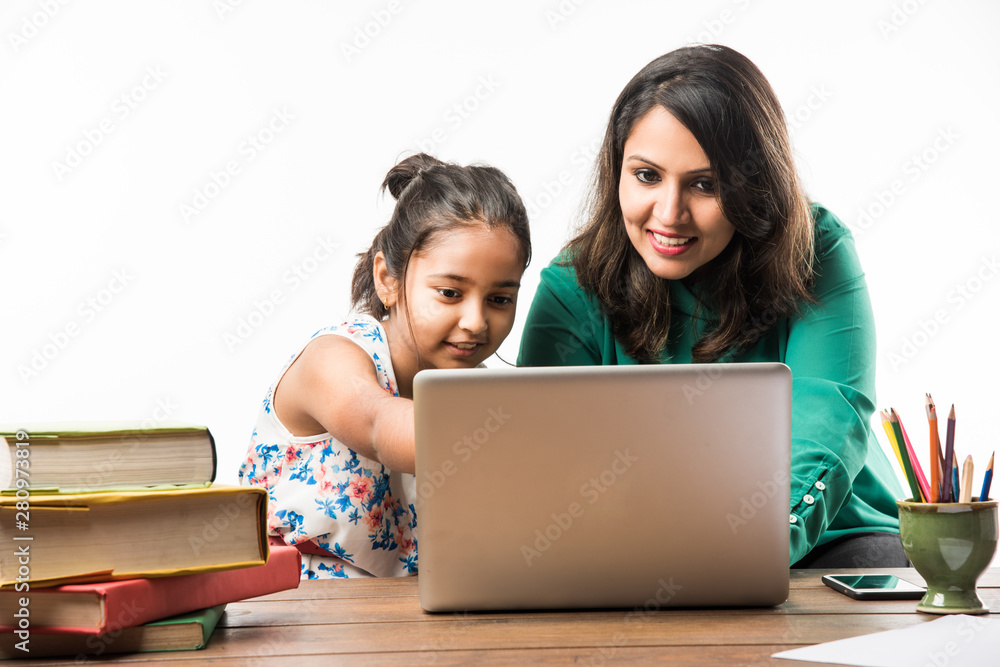 Indian girl studying with mother or teacher at study table with laptop ...