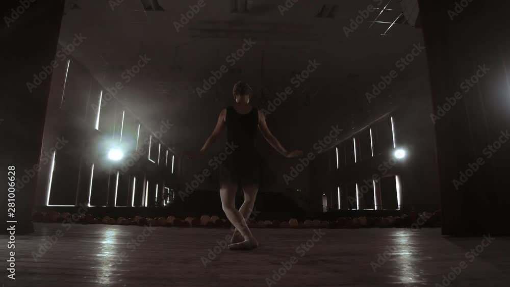 Slow motion: the prima ballerina in a black dress performs rotations ...