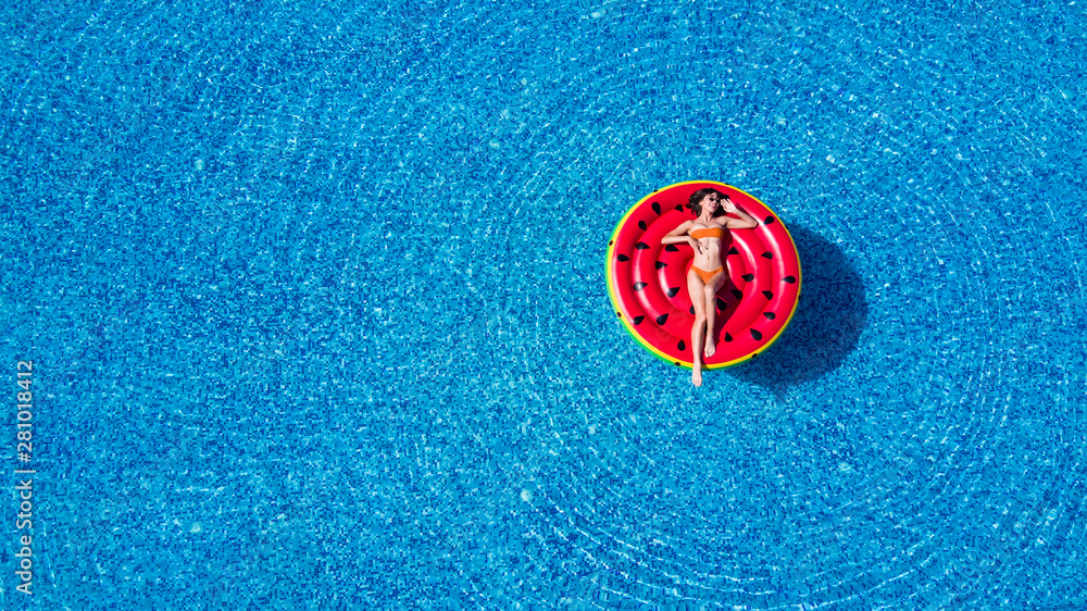 Aerial view of woman in bikini lying on a floating mattress in swimming ...