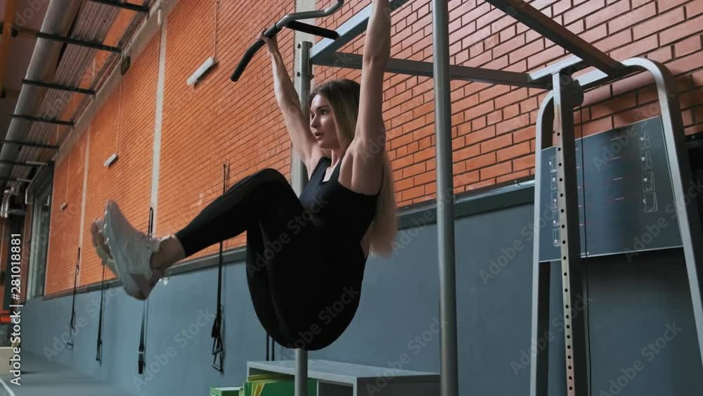 Young woman training abs hanging on horizontal bar. Beautiful blonde ...