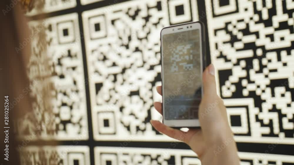 Woman using smartphone scans large QR codes on the interactive wall of ...