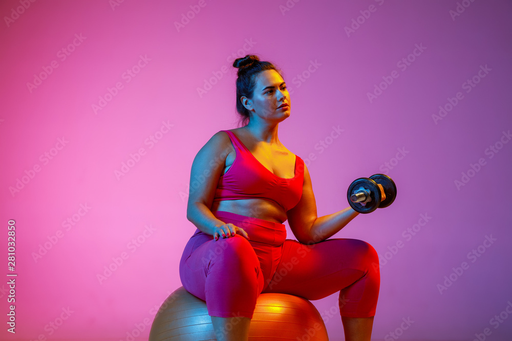 Young caucasian plus size female model's doing exercises on gradient ...