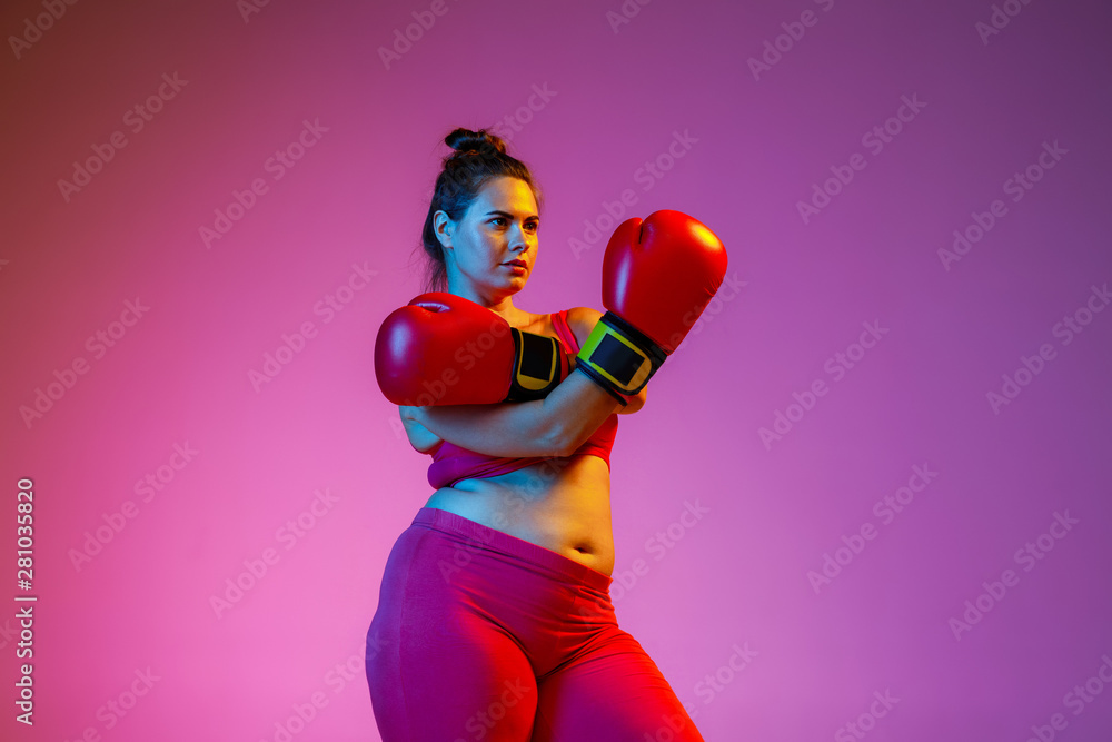 Young caucasian plus size female model's doing exercises on gradient ...
