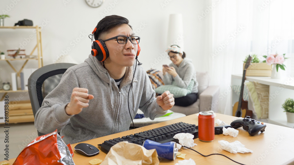 Angry young male gamer in glasses playing game on computer using ...