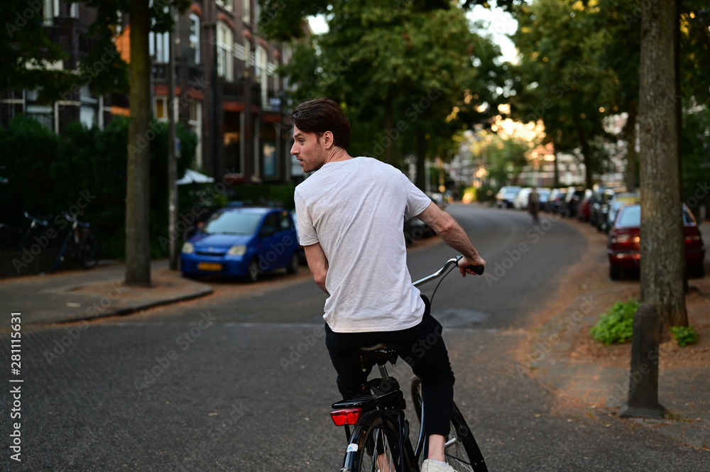 Dutch male student manoeuvring his bicycle on a nice and cosy old Dutch ...