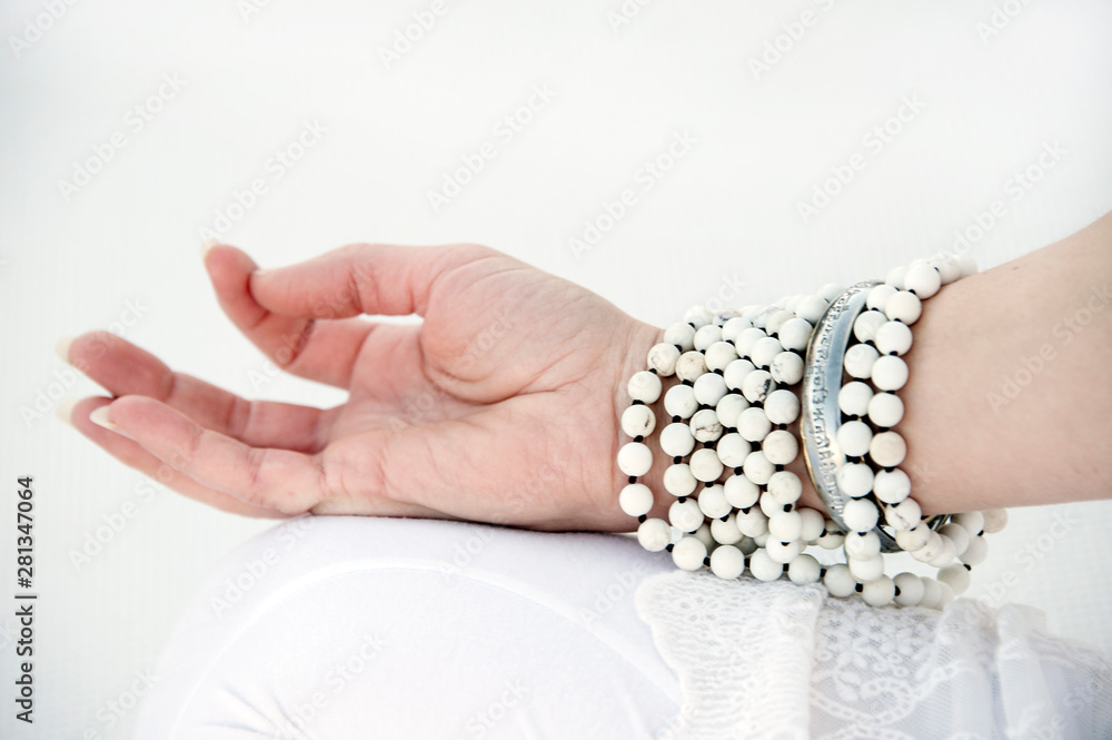The hand and wrist of a woman wrapped with yoga mala her fingers in a ...