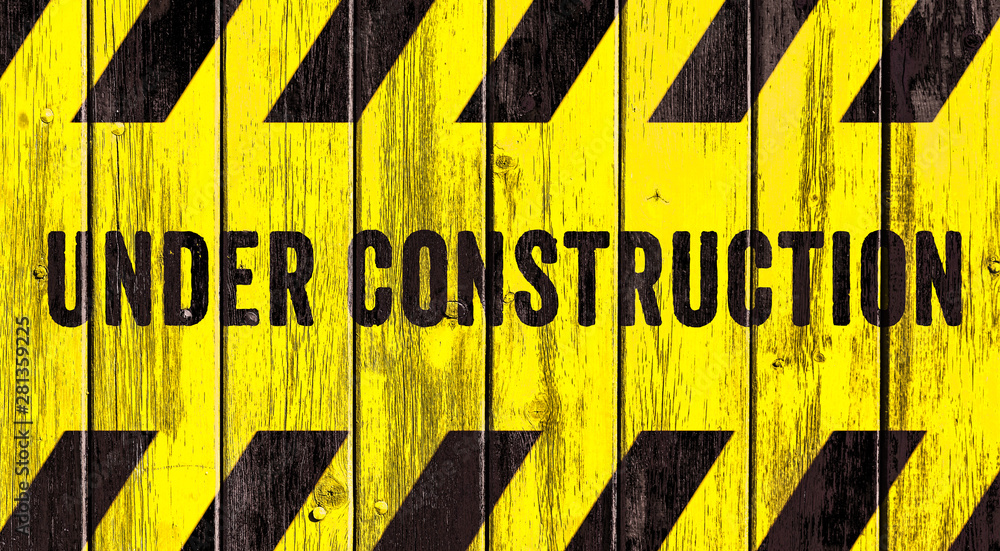 Under construction warning sign text with yellow black stripes painted ...