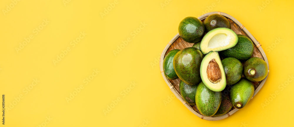 organic avocados half cut with seed and whole fruit in bamboo basket on ...