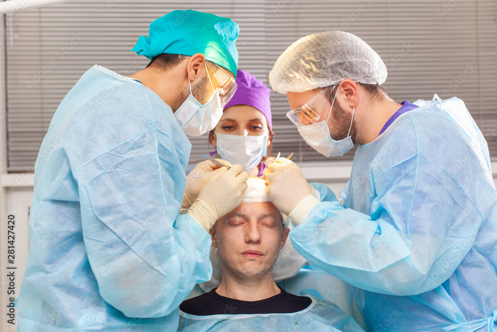 Baldness treatment. Hair transplant. Surgeons in the operating room ...