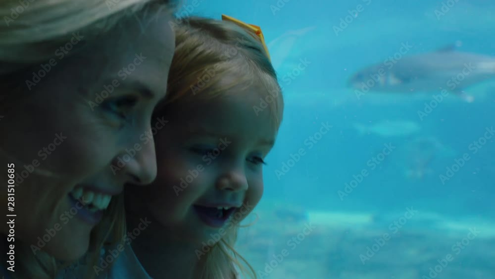 happy mother with daughter at aquarium looking at beautiful fish ...