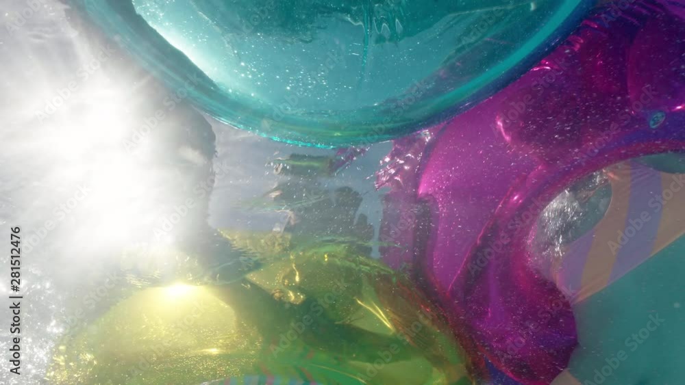 children splashing in swimming pool with multicolor swim tube ...