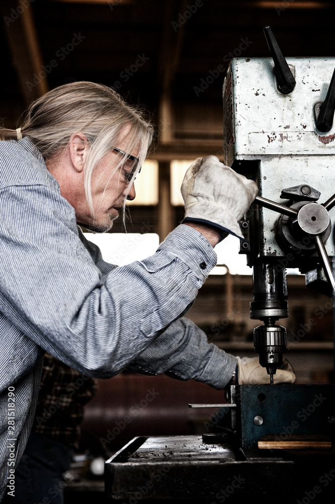 Side view of worker using drill press in factory Stock Photo | Adobe Stock