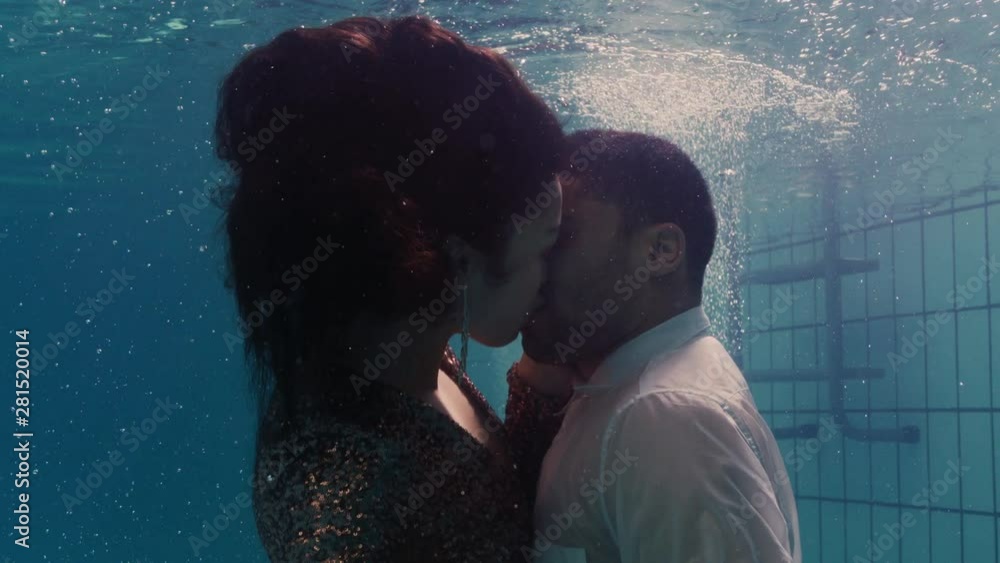 romantic couple kissing underwater in swimming pool wearing clothes ...