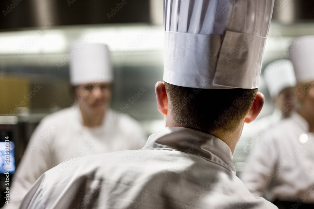 Rear view of chef wearing toque hat in commercial kitchen Stock Photo ...