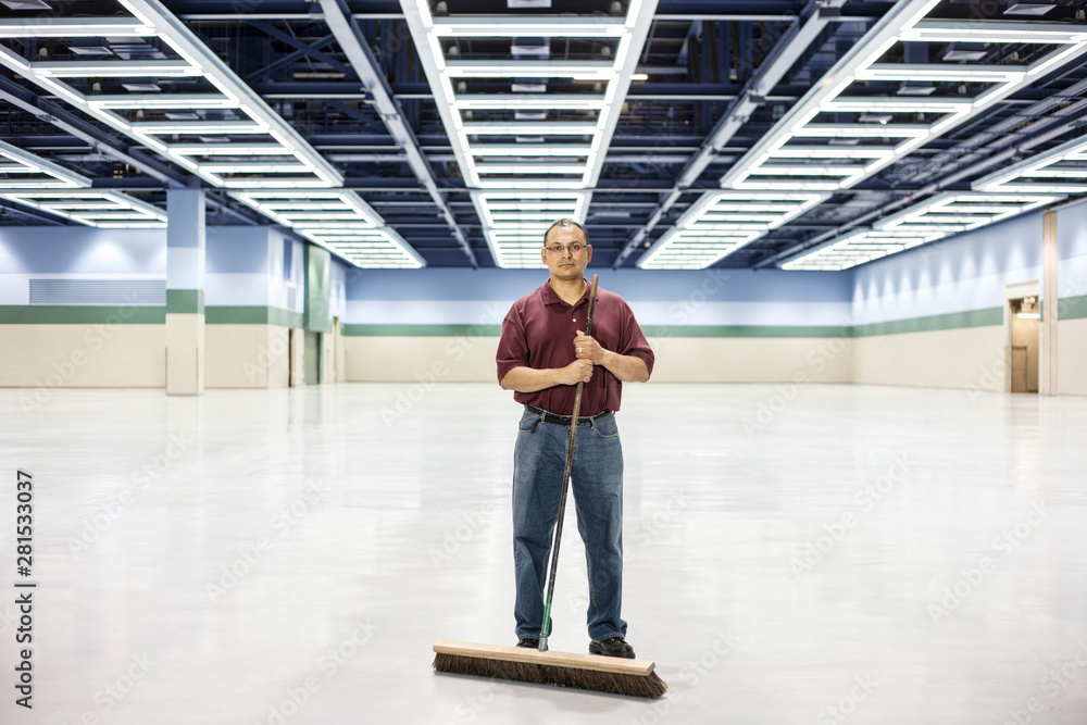 Portrait of man standing with broom at convention center Stock Photo ...