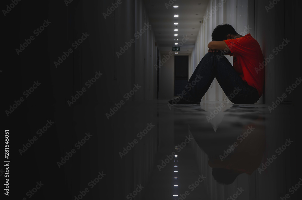 Side view of Asian young man sitting at the corridor looks disappointed ...