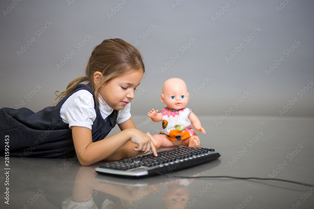 The little girl the schoolgirl on a gray background plays with the ...