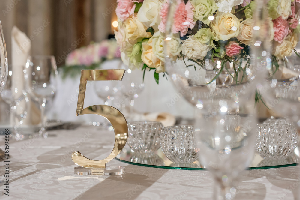 Golden number five on a decorated table for a wedding dinner. Festive ...