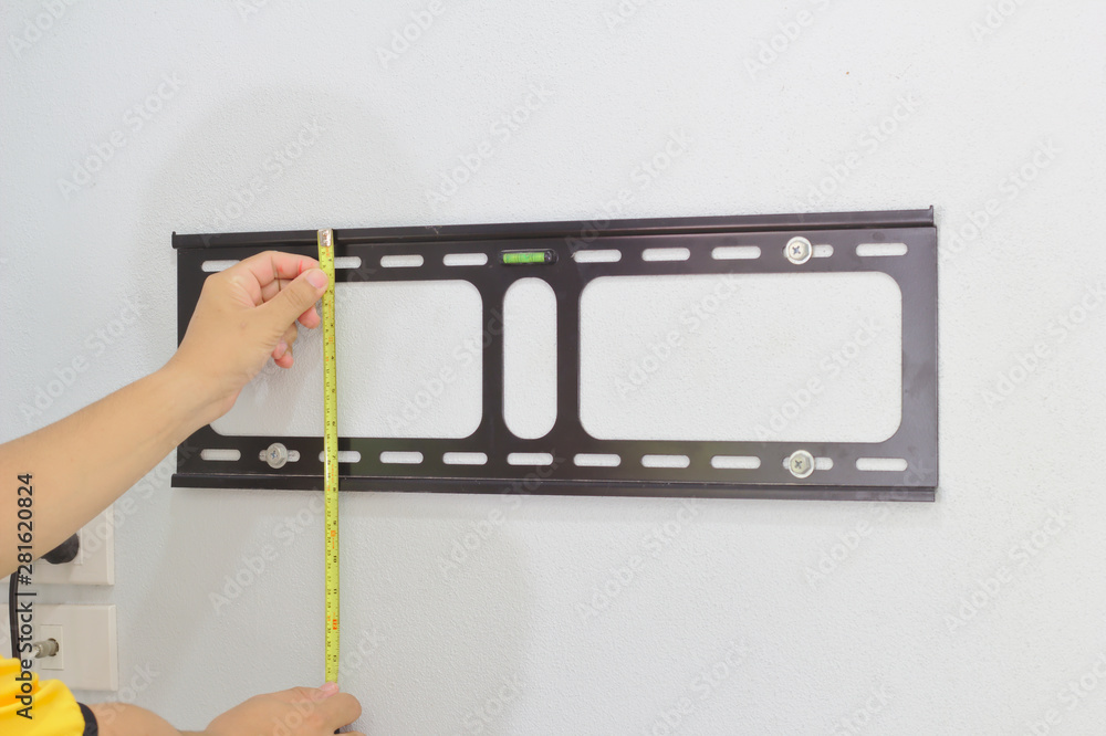The technician installs the device to hang the TV on the wall. Measure ...