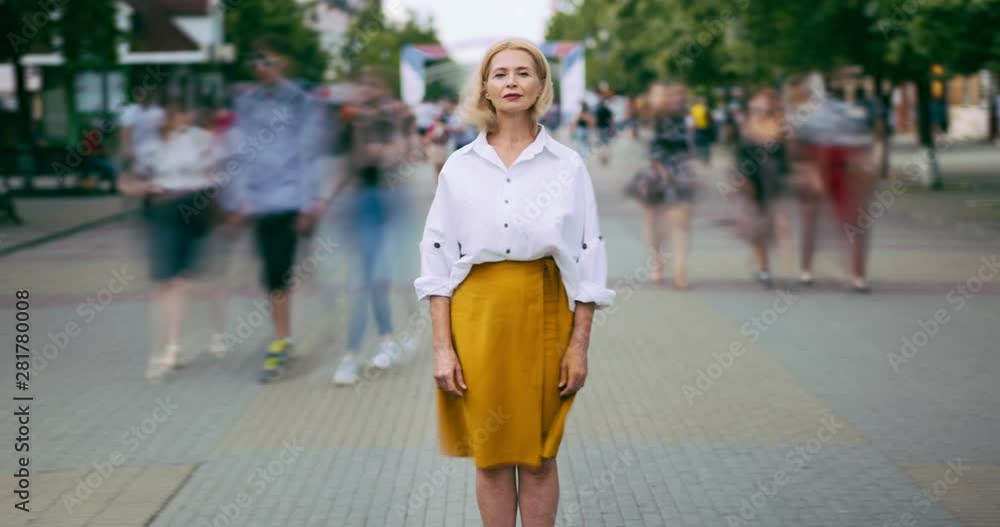 Zoom out time lapse of pretty mature woman looking at camera standing ...