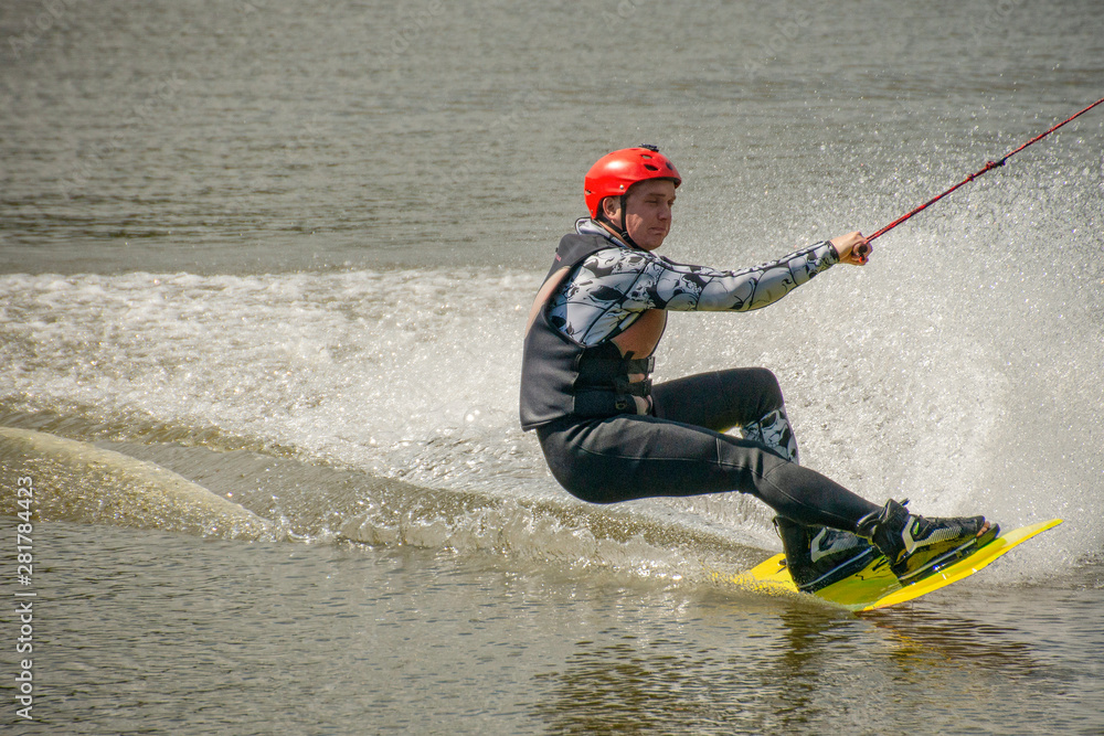 Sliding on the water surface sportsman wakeboarder with lots of silver ...