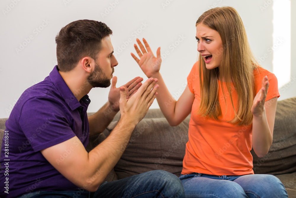 Angry wife and husband are having conflict while they sitting on sofa ...